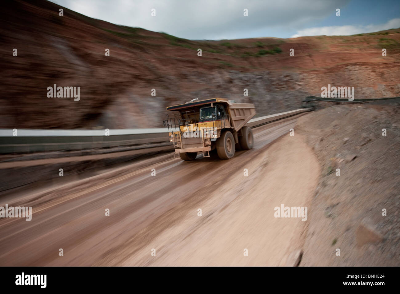 Heavy earth mover haul dump truck in open cast mine delivering rocks to ...