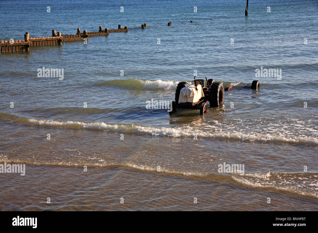 Tractor and boat trailer in the sea at Overstrand, Norfolk, England ...