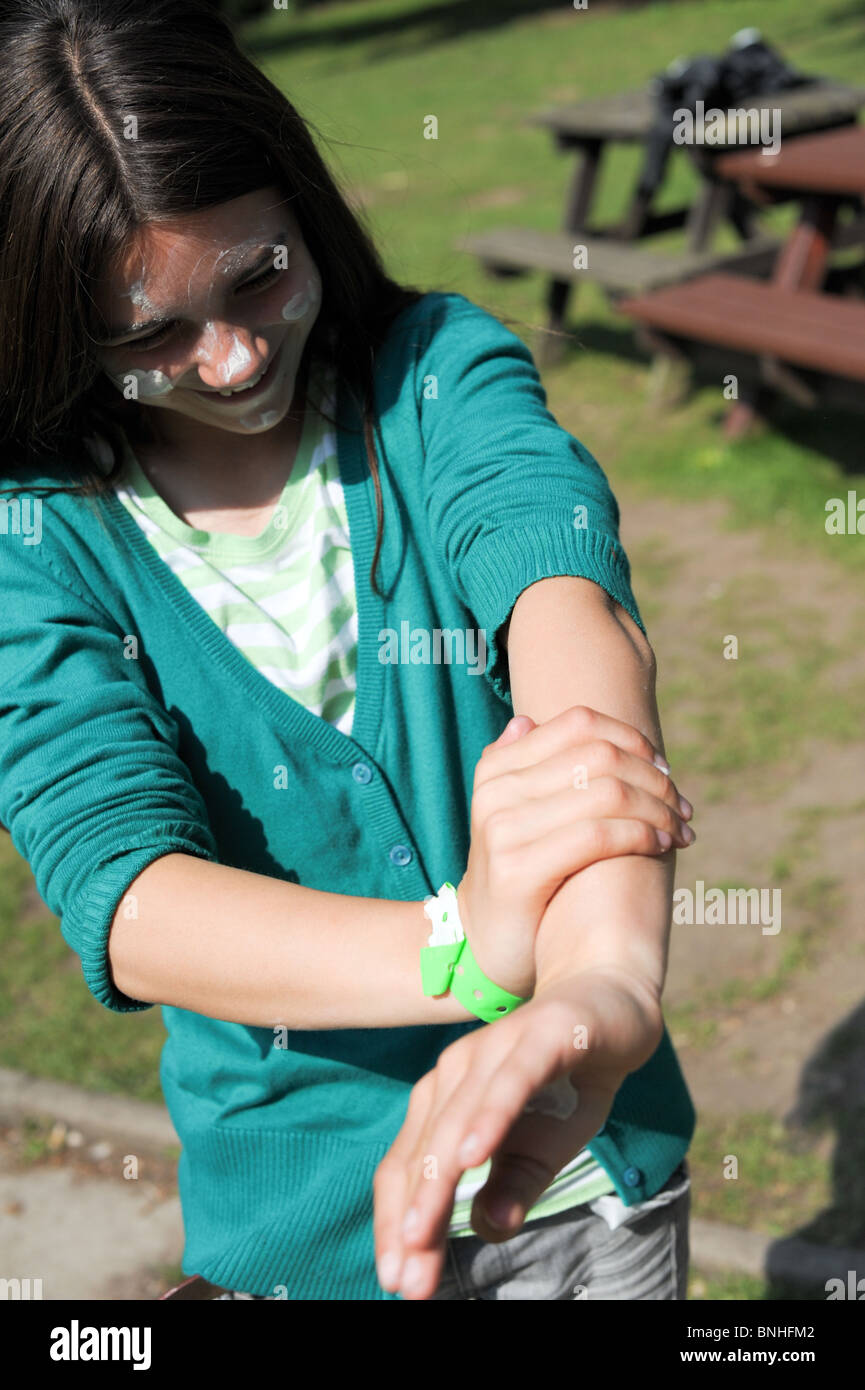 Girl happily rubs suncream to protect her face and arms from sunburn in ...