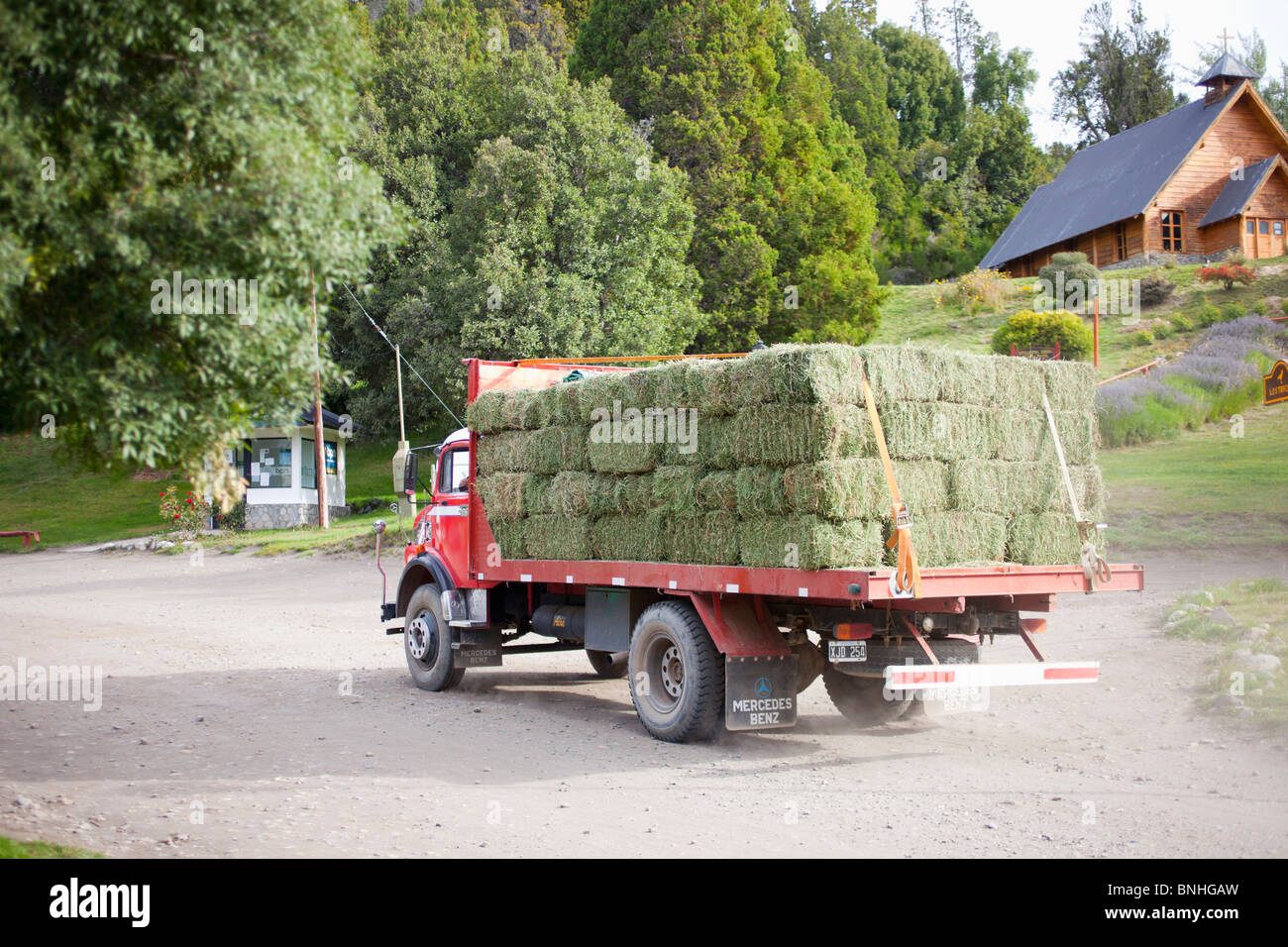 Truck carrying hay bails driving through a village Stock Photo - Alamy