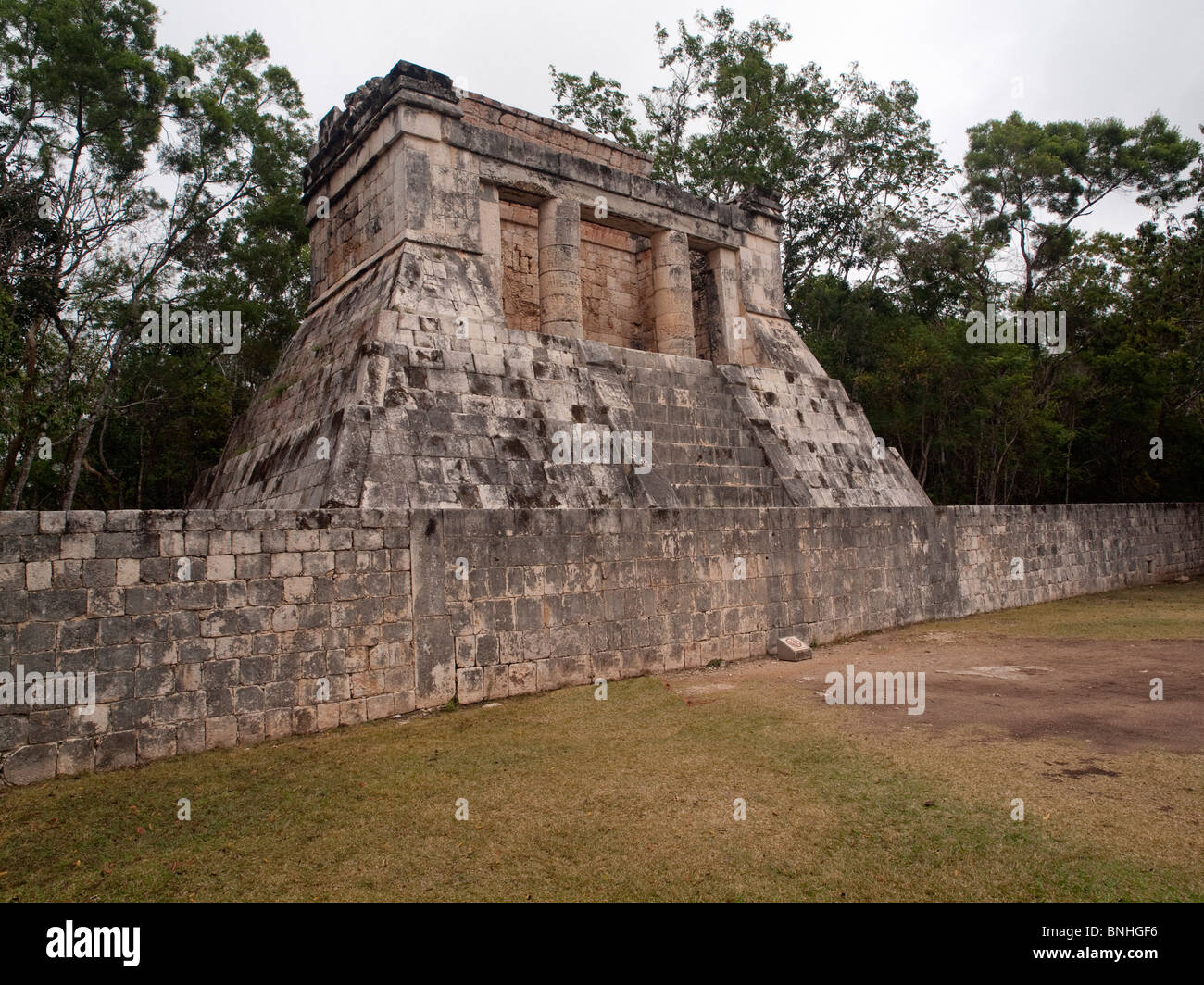 Pyramid with the ruins of the temple and a stone wall at Chichen Itza ...