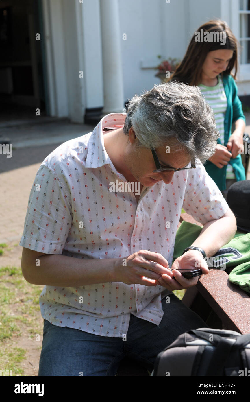 A grey-haired dad sends a text message with his daughter nearby Stock ...