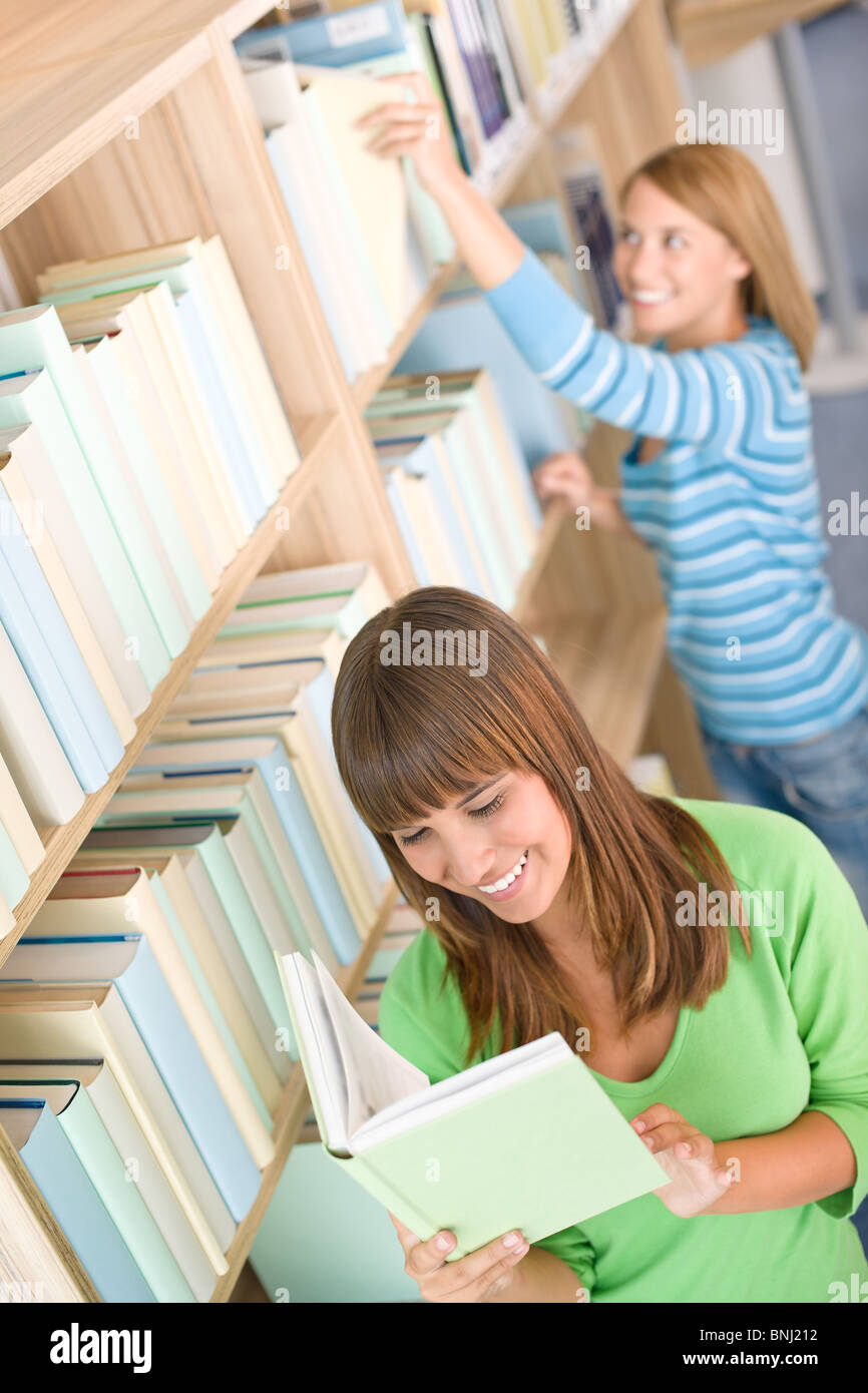 Student in library - two woman choose book from bookshelf Stock Photo ...