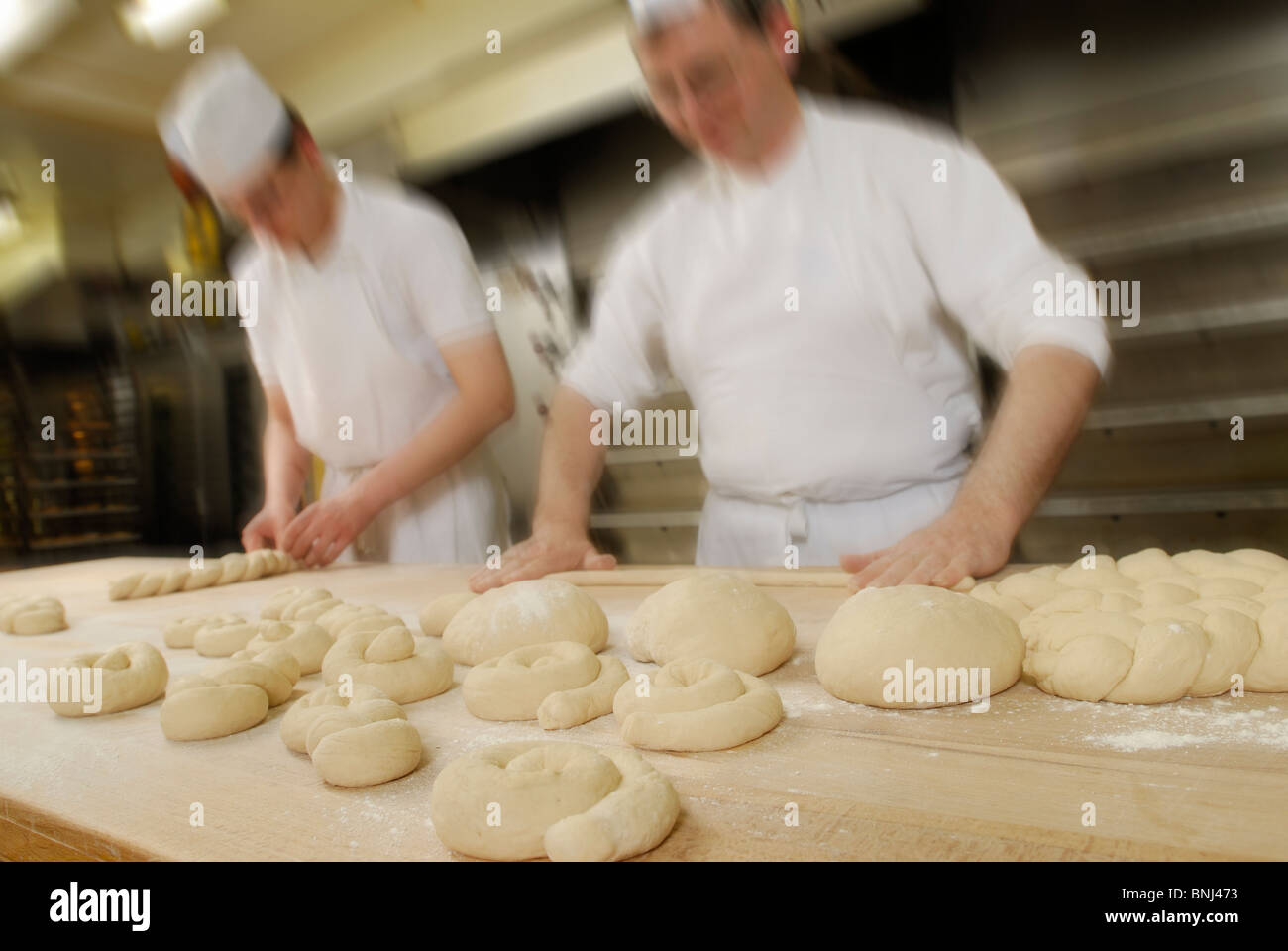 two baker, blurred, forming cakes out of pastry Stock Photo - Alamy