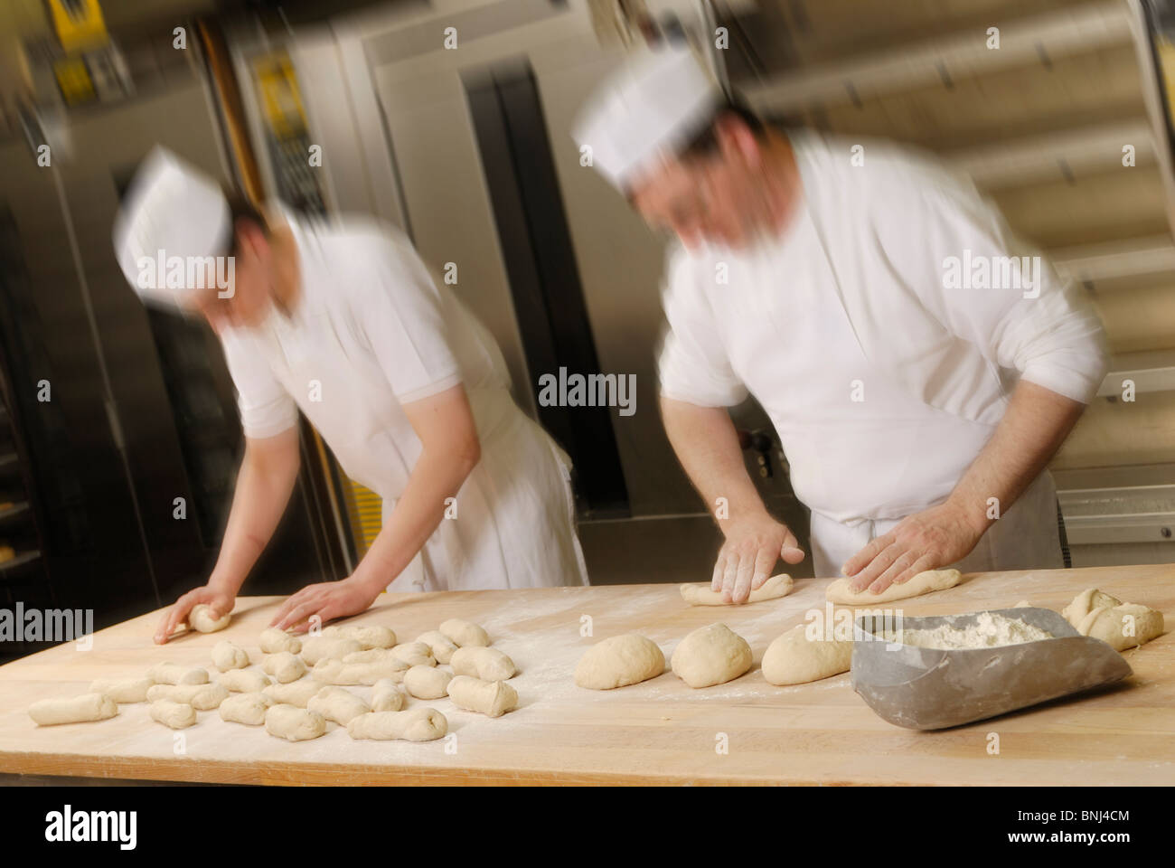 two baker, blurred, forming cakes out of pastry Stock Photo - Alamy