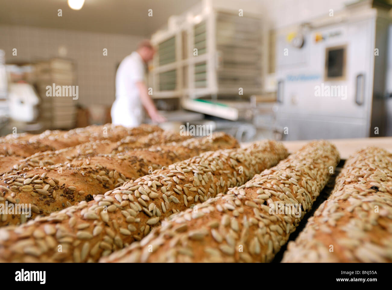 completed bread rolls in front, blurred working baker behind Stock ...
