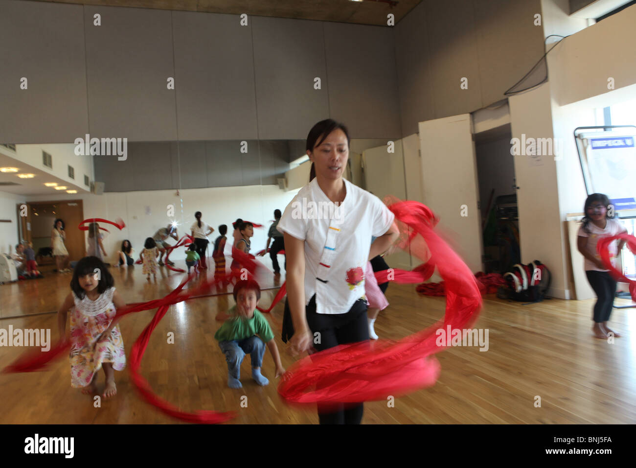a oriental woman doing a traditional ribbon dance in a dance studio ...