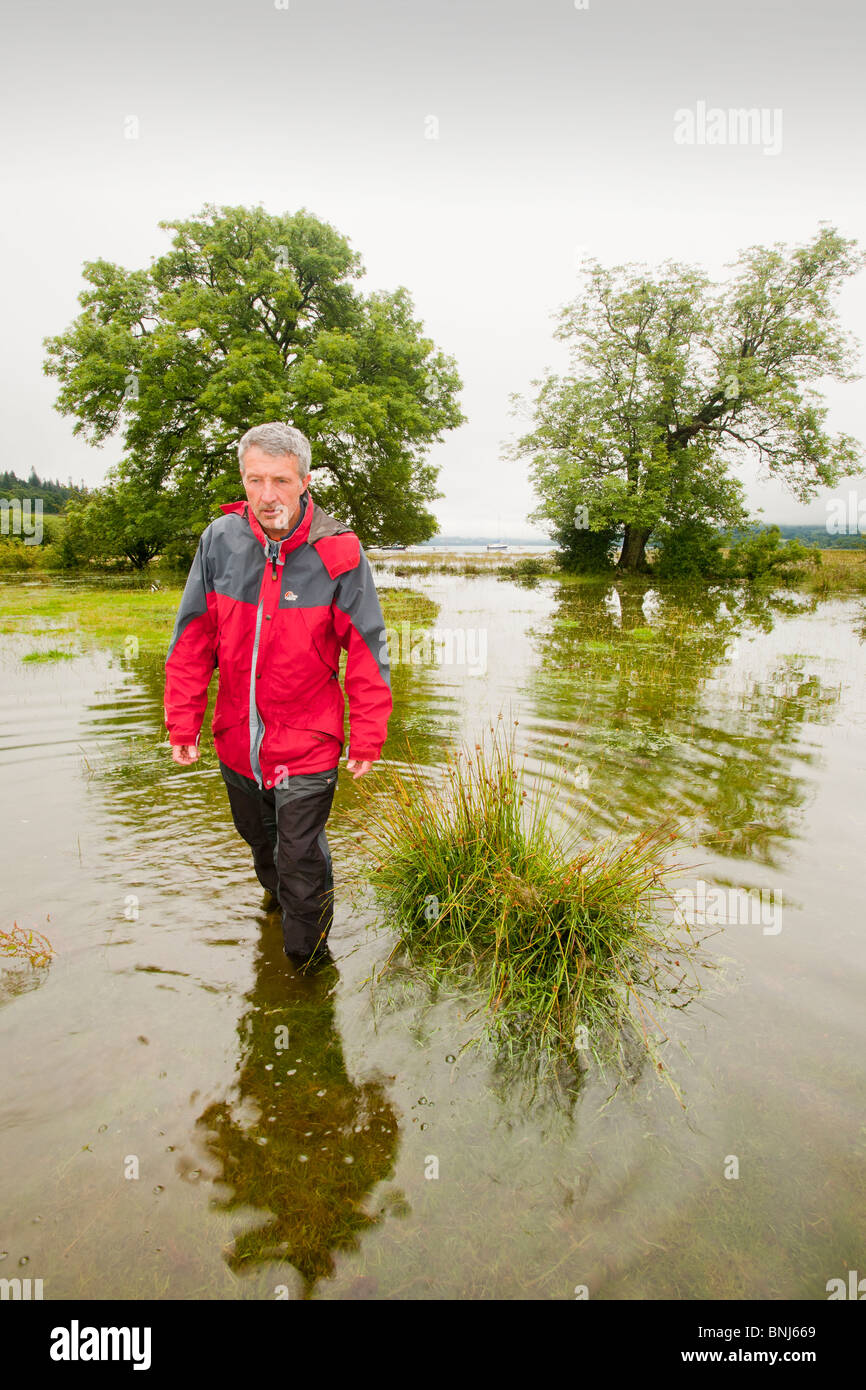 A man wading through flood waters at the edge of Lake Windermere in ...