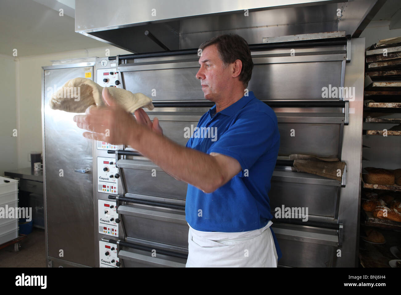 a baker stood in front of a bread oven throwing some bread dough in the ...