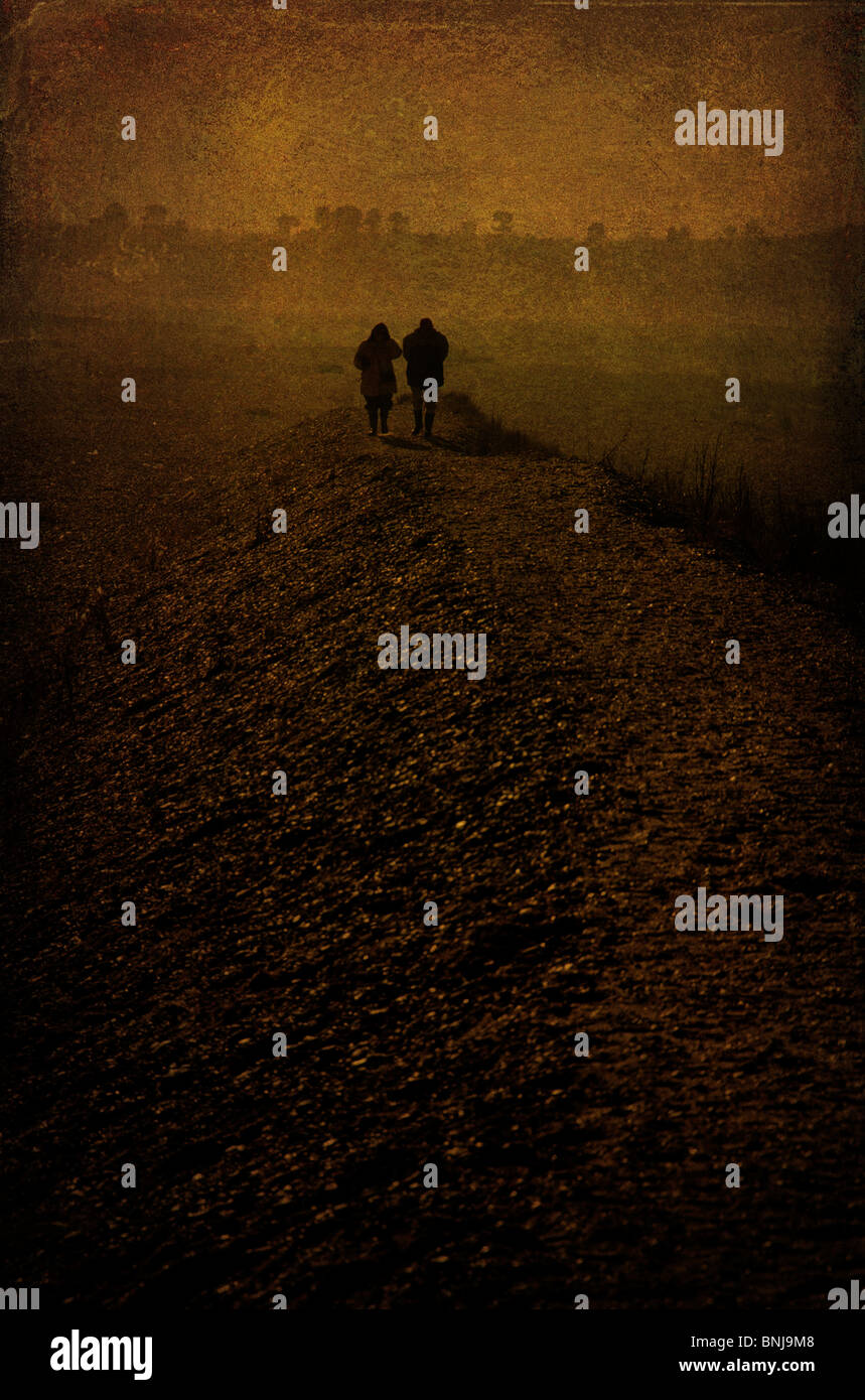 Two figures walking along a beach into the distance on a cold day in ...