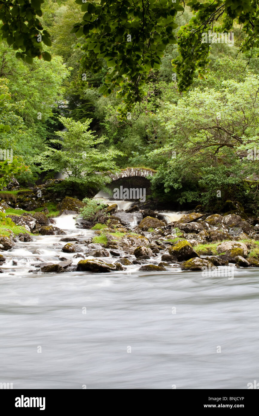Stone bridge over fast flowing river Stock Photo - Alamy