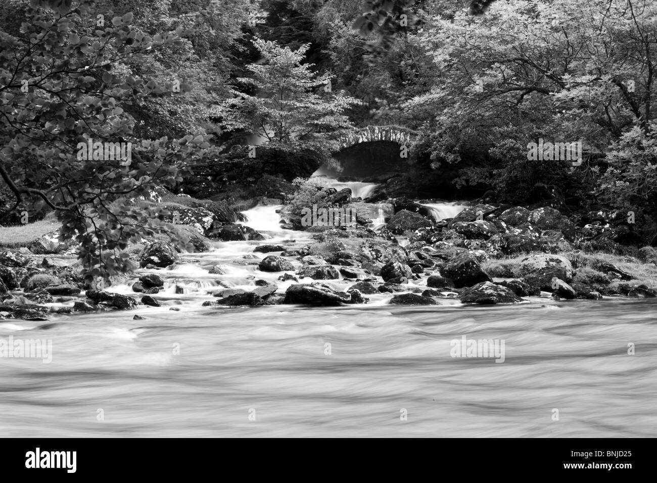 Stone bridge over fast flowing river Stock Photo - Alamy