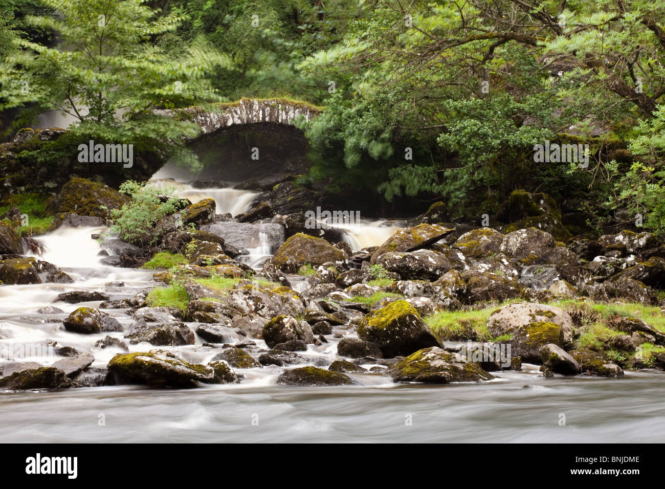 Stone bridge over fast flowing river Stock Photo - Alamy