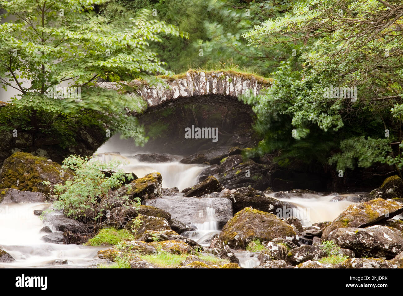 Stone bridge over fast flowing river Stock Photo - Alamy