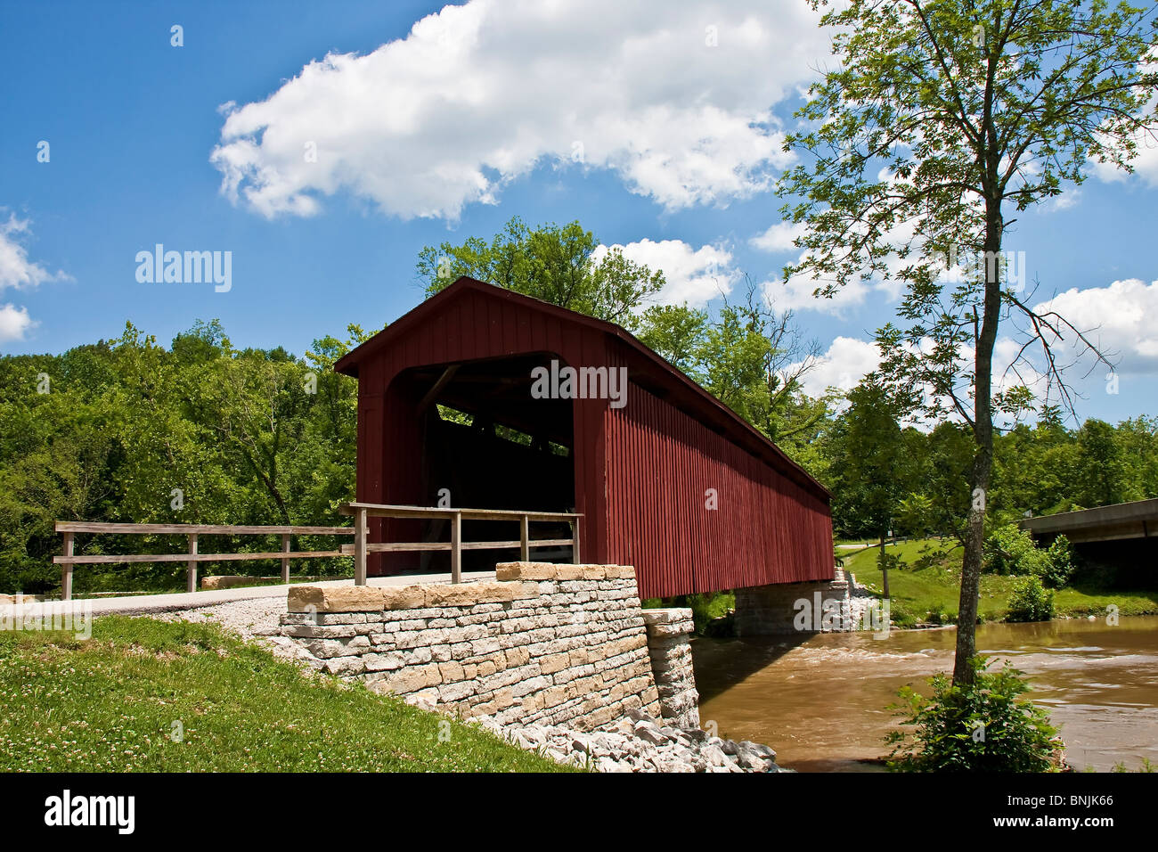 An old red covered bridge b y a stone wall under nice sky Stock Photo ...