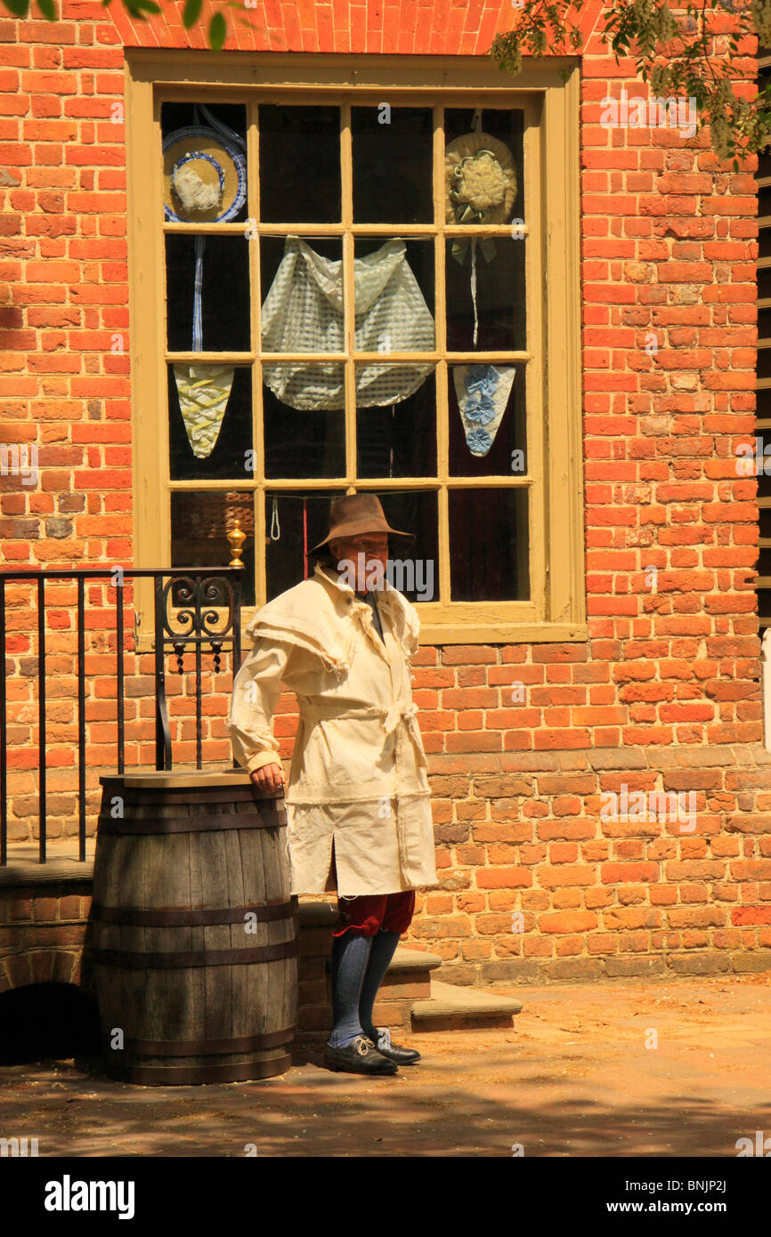 A costumed Interpreter stands outside his shop in the Historic Area ...