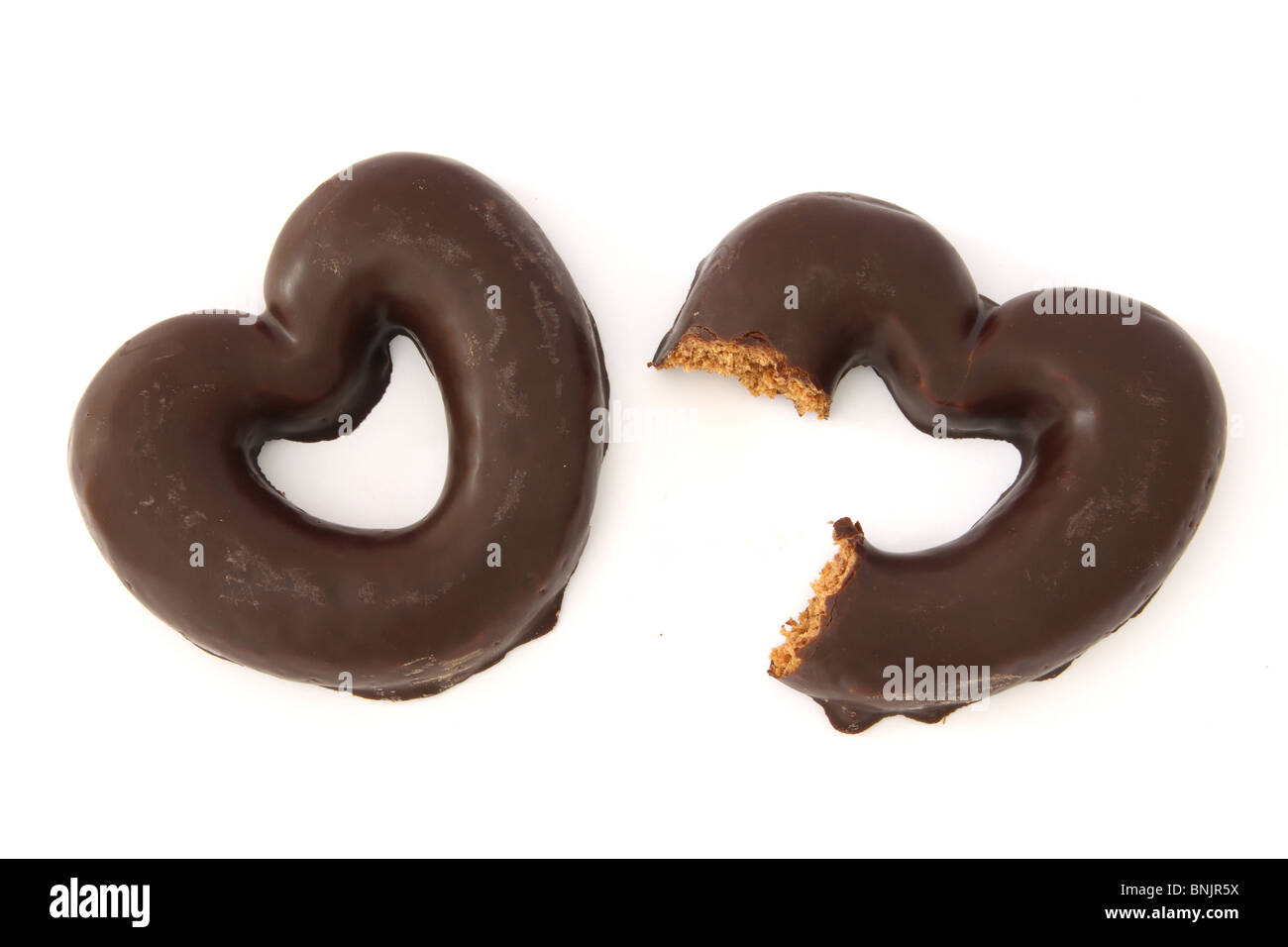 Two gingerbread hearts covered with chocolate, one partially bitten ...