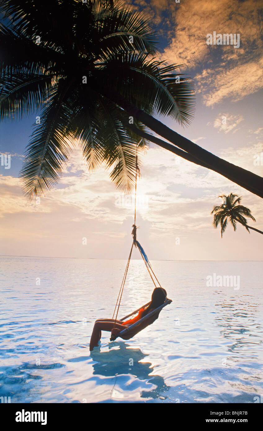 Woman in swing chair hanging from palm tree on Meeru Island in Maldives ...