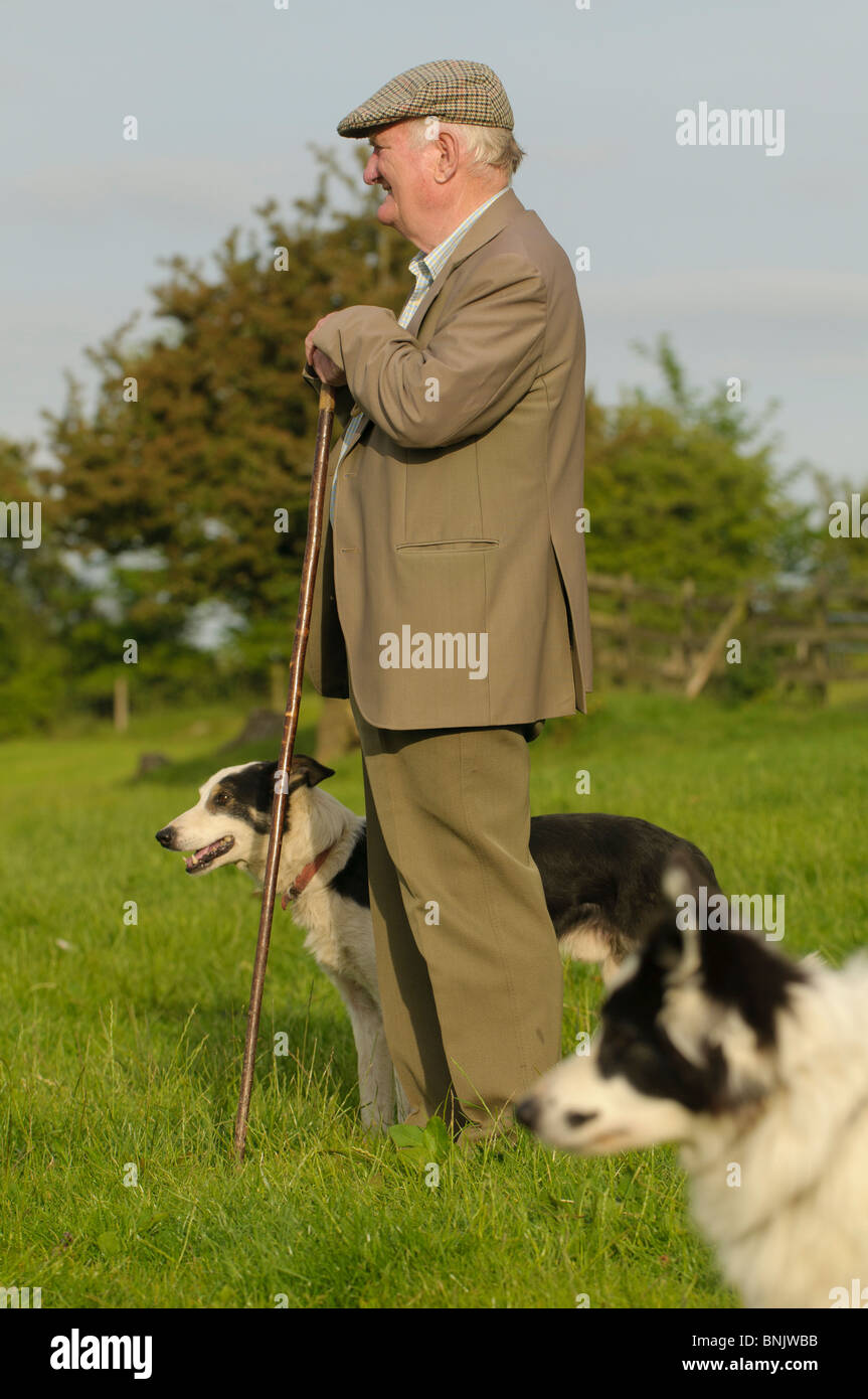 A farmer with his sheepdog watching Sheepdog trials on a farm in west ...