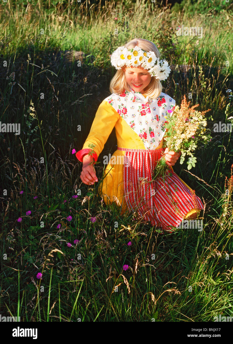 Girl in colorful Midsummer dress picking wildflowers in Sweden in June ...