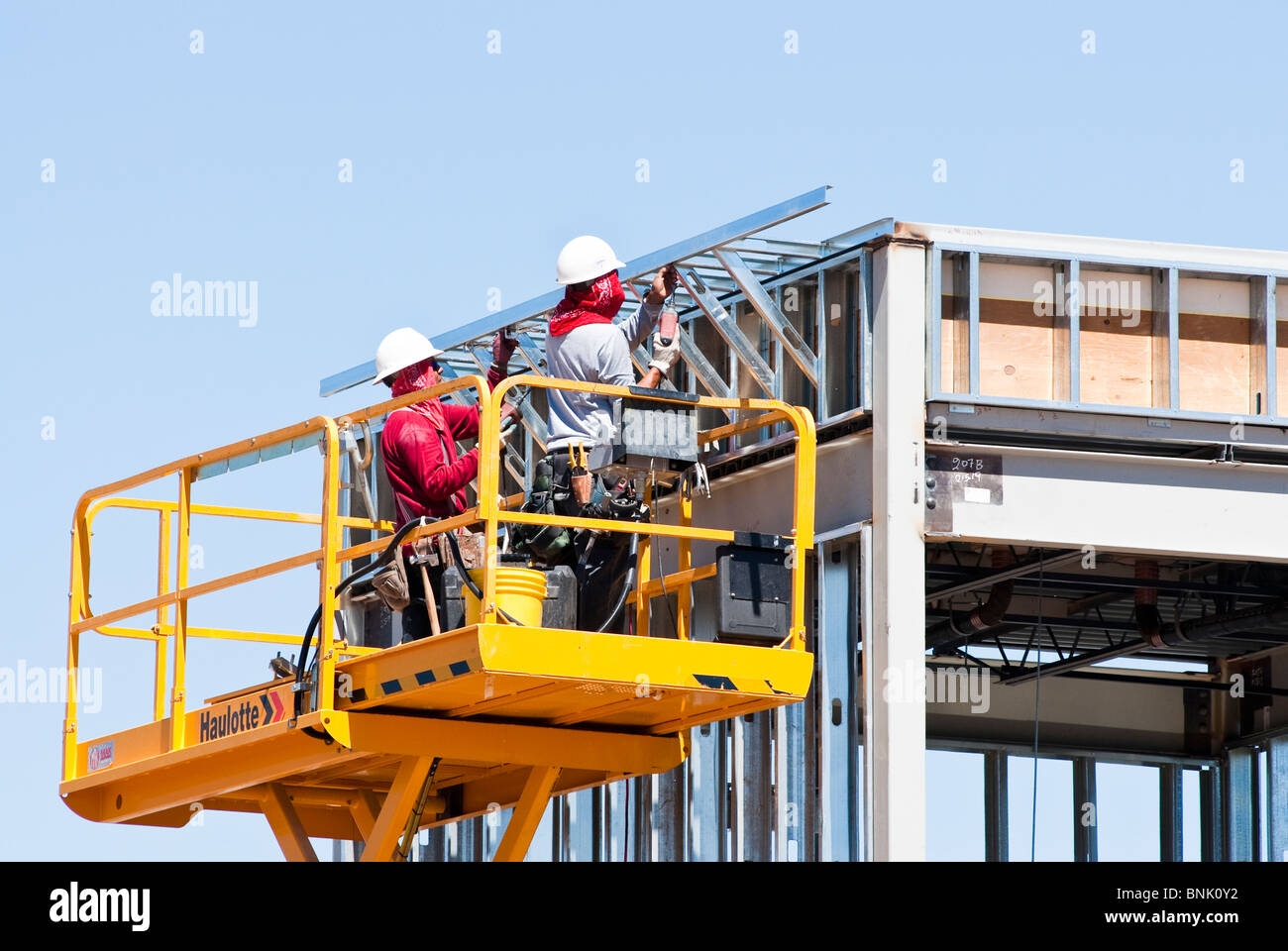 Construction workers on a scissor lift platform are assembling ...