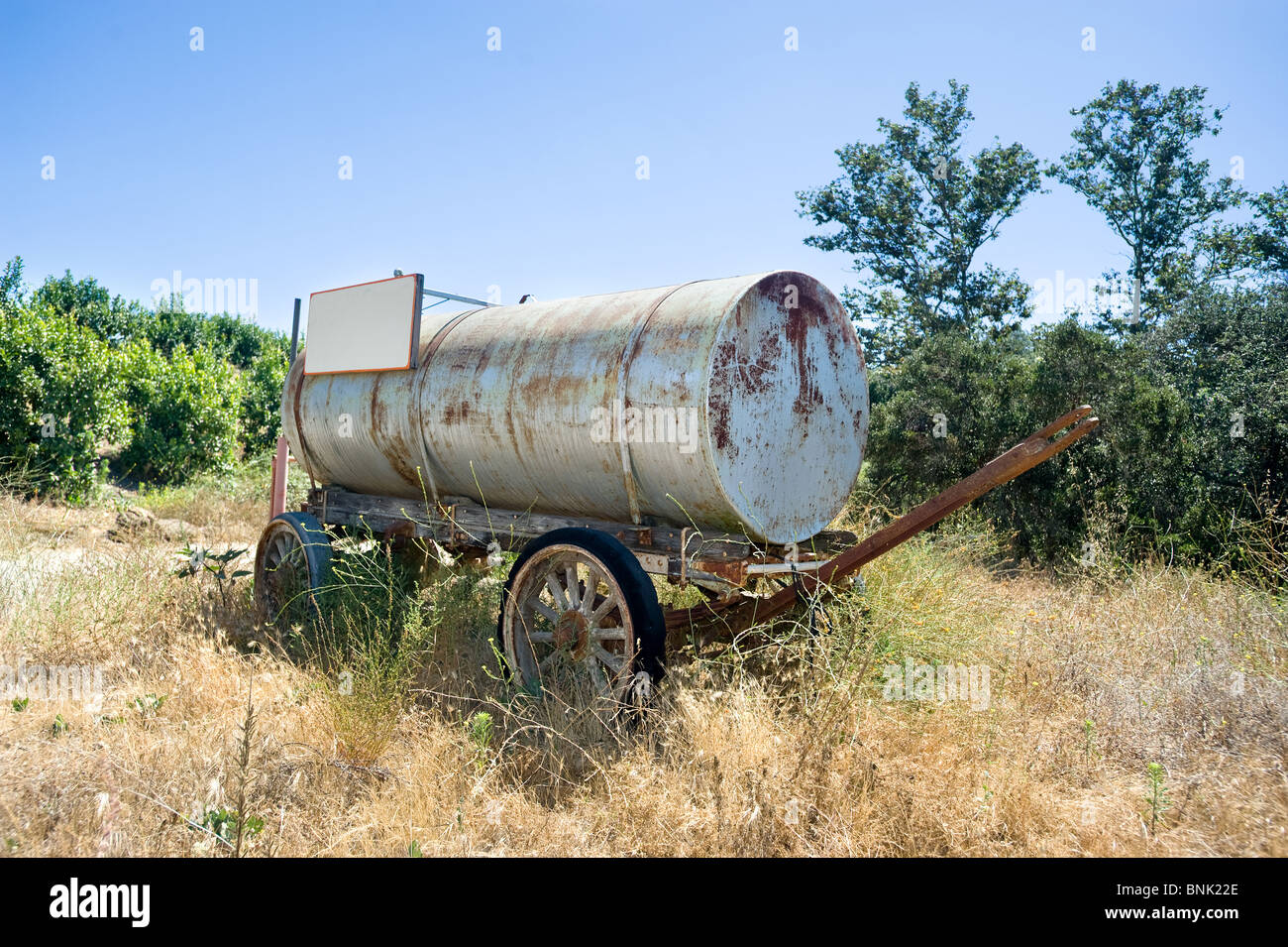 An antiquated horse drawn water cart in a rural area during the daytime ...