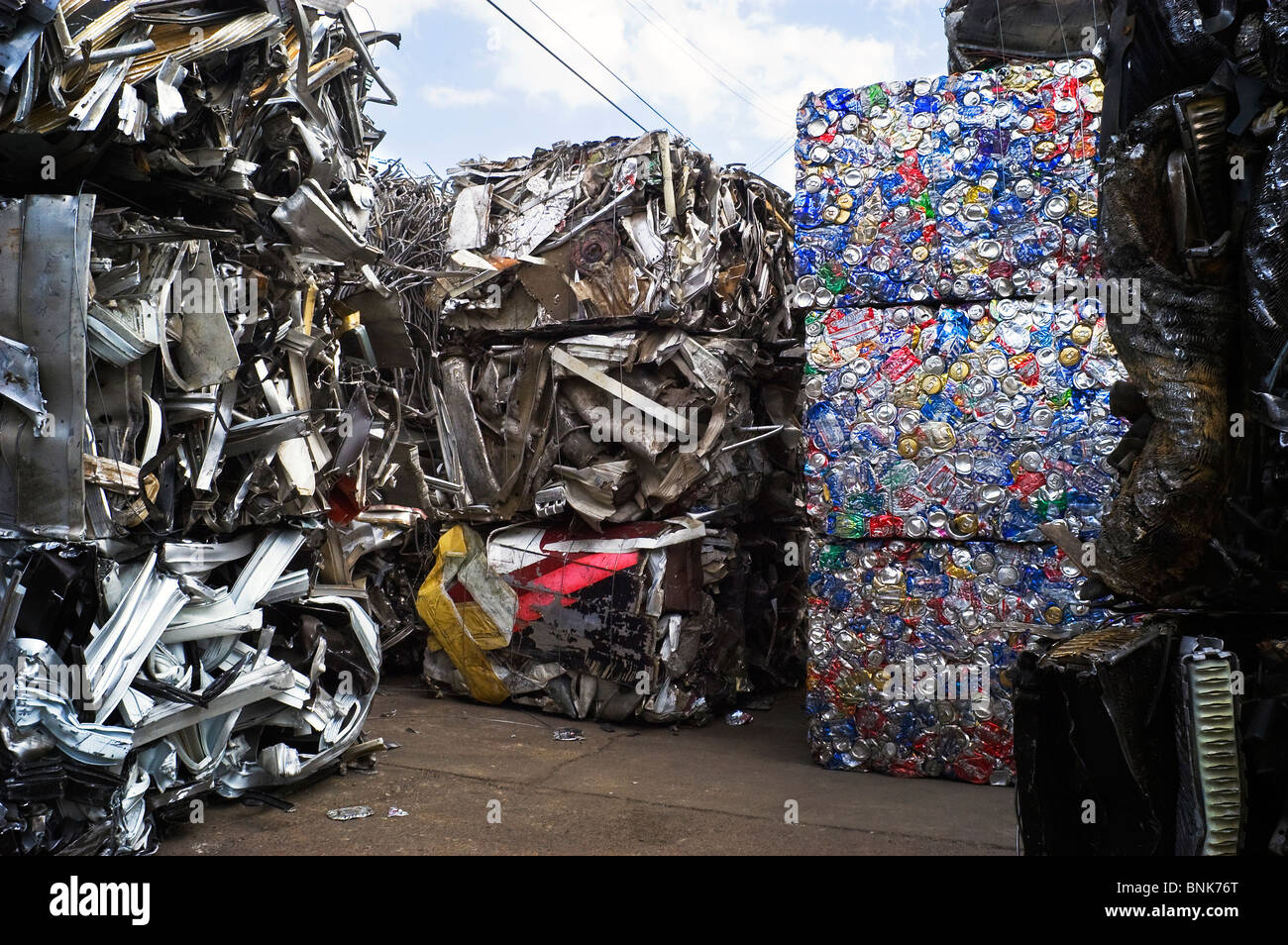 Bales of crushed scrap metal sit waiting in a recycling yard, ready for ...