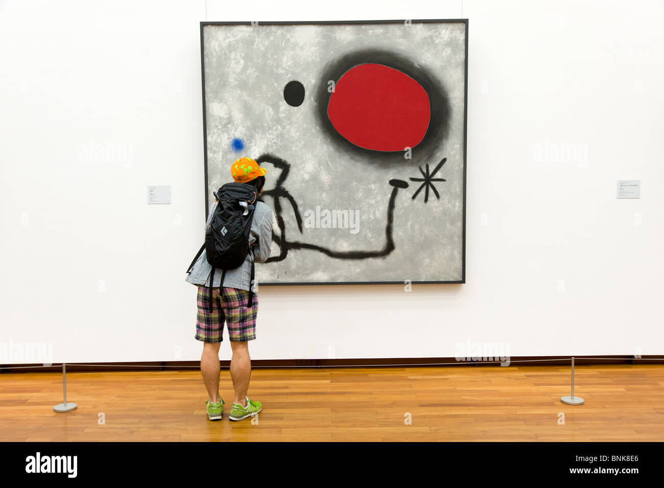 Young man looking at modern art oil painting by Joan Miro in the ...