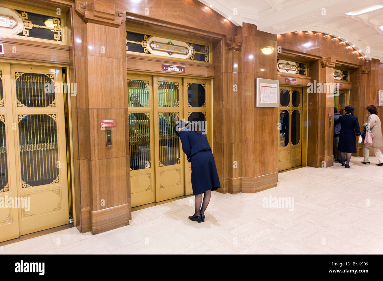 Shop worker bowing to ascending lift in Takashimaya department store ...