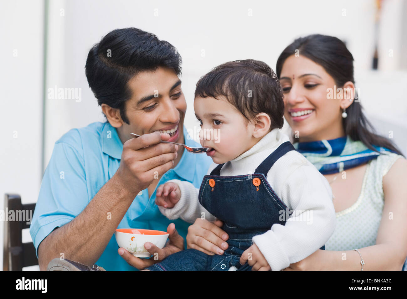 Couple feeding baby food to their son Stock Photo - Alamy