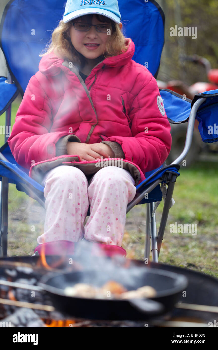 Happy young girl cooking breakfast on a campfire Stock Photo - Alamy