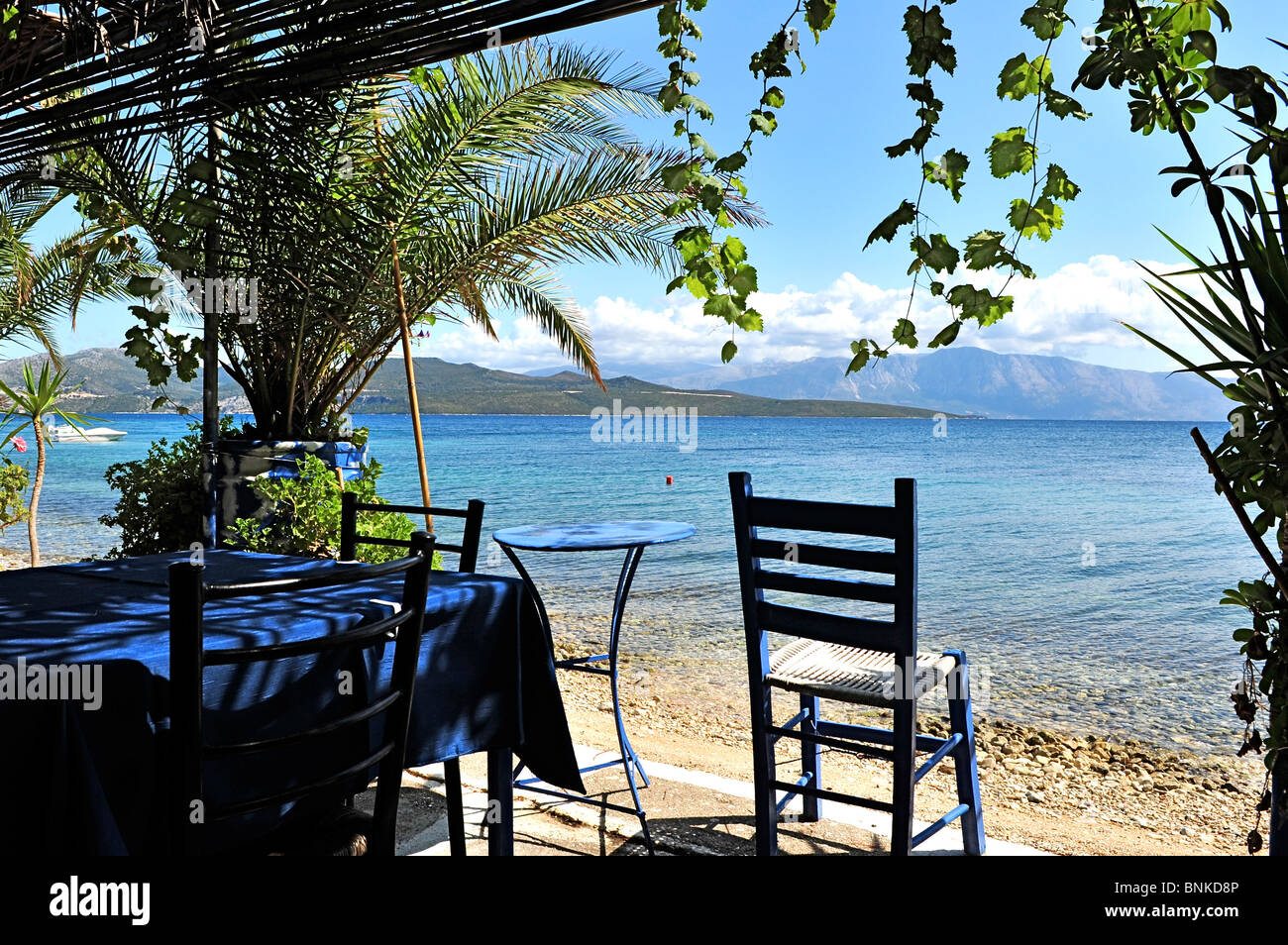 A typical rustic Greek restaurant with blue painted tables and chairs ...