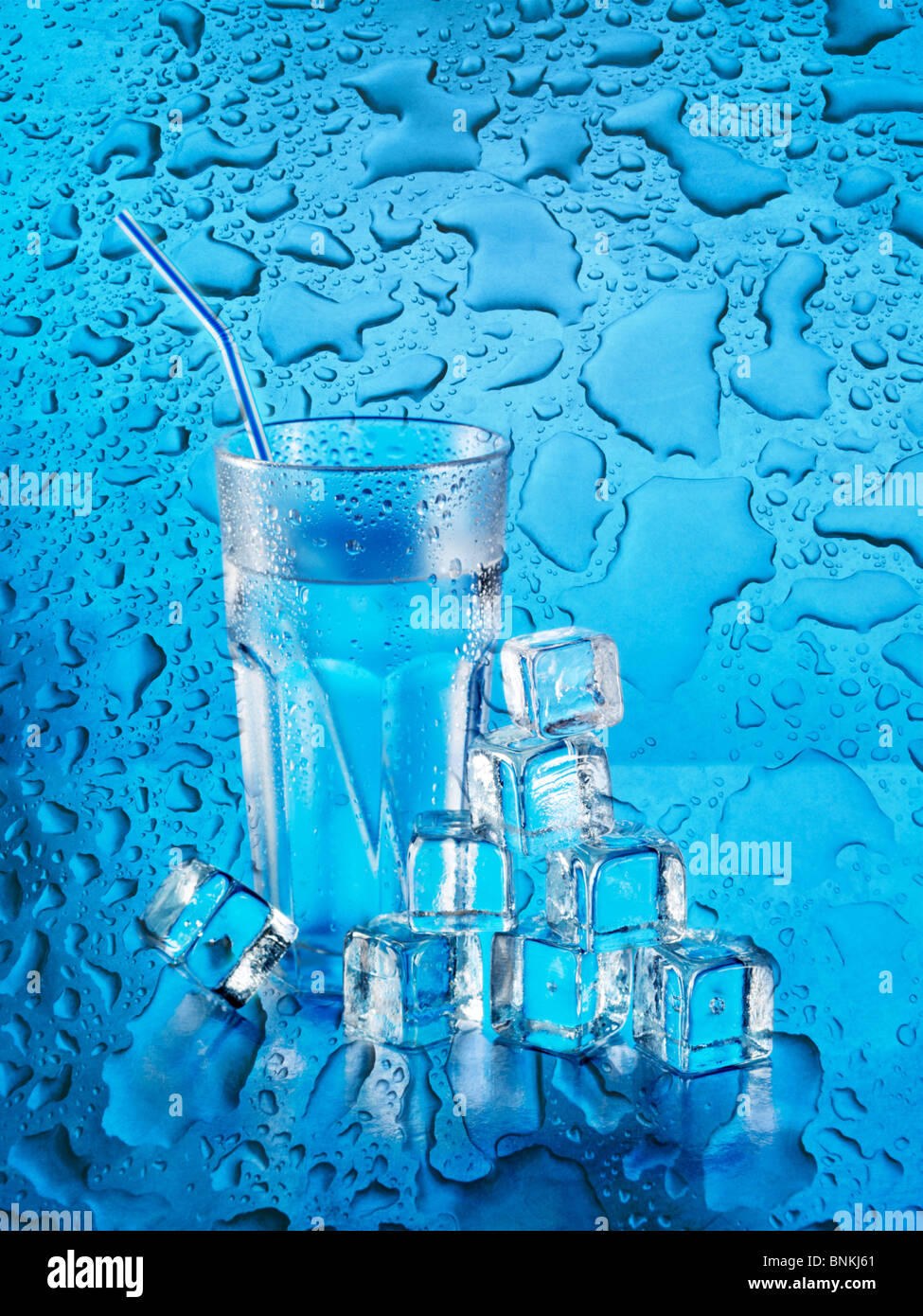 A glass of iced water with ice cubes and drinking straw and water ...