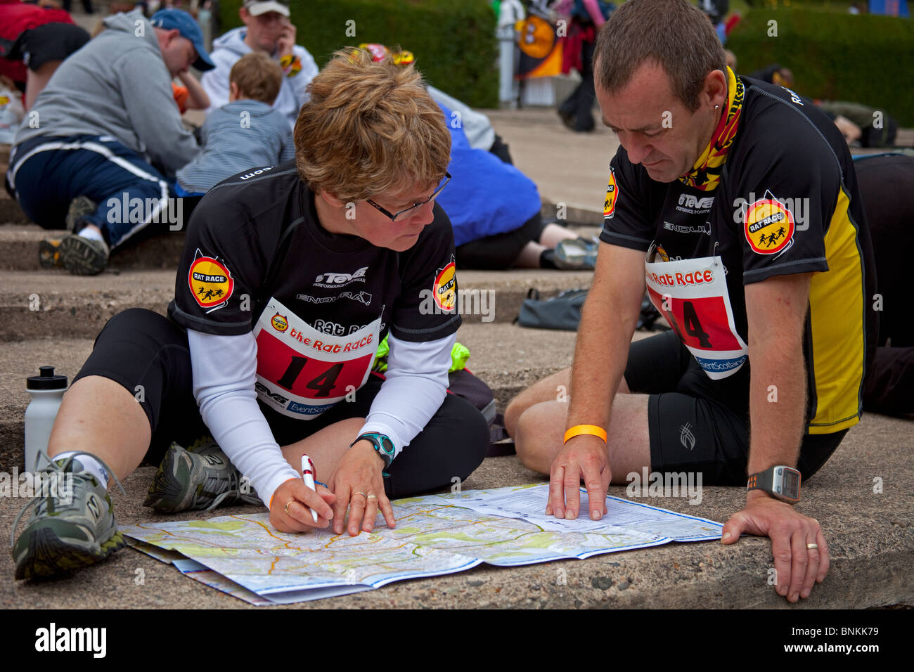 male female Rat Race competitors examine route map, Edinburgh Scotland ...