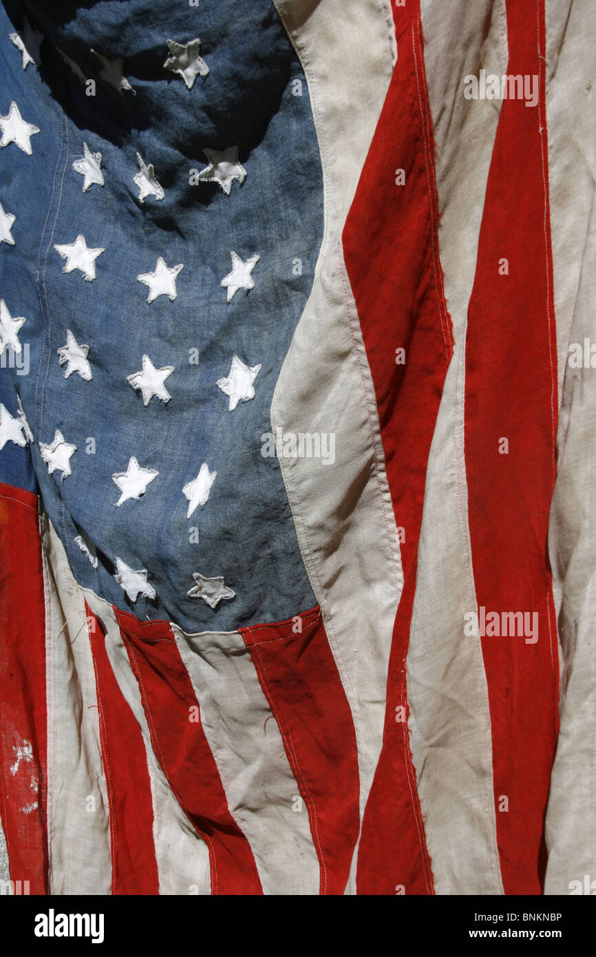 one old american flag hanging on wall outside in sun Stock Photo - Alamy