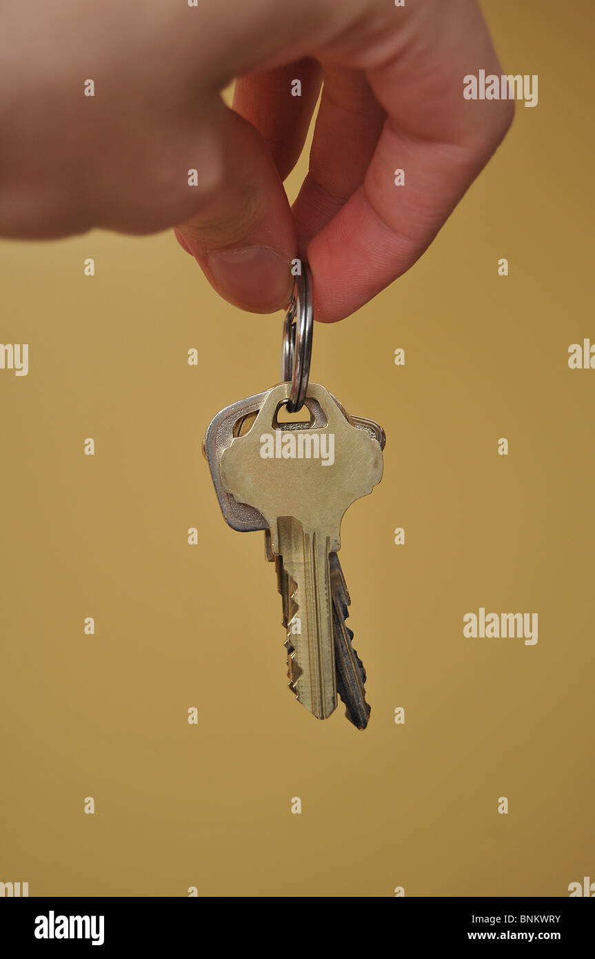 Hand holding keys with yellow background Stock Photo - Alamy