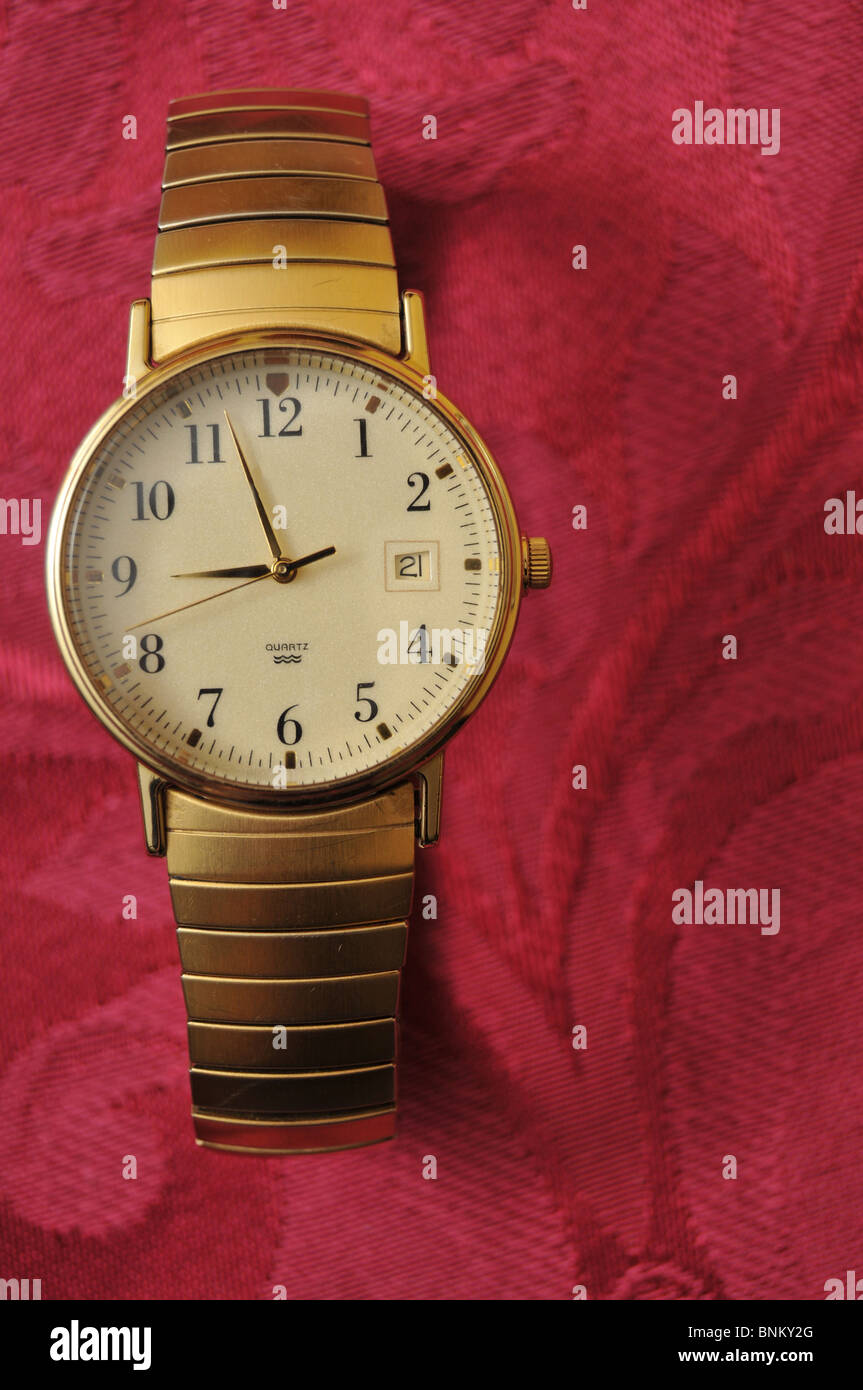 Golden watch laying on red cloth Stock Photo - Alamy