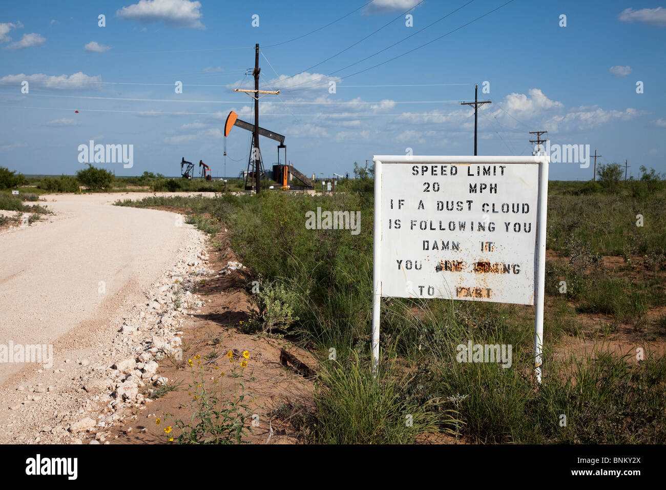 Speed limit sign on dirt road concening dust cloud in oil drilling area ...