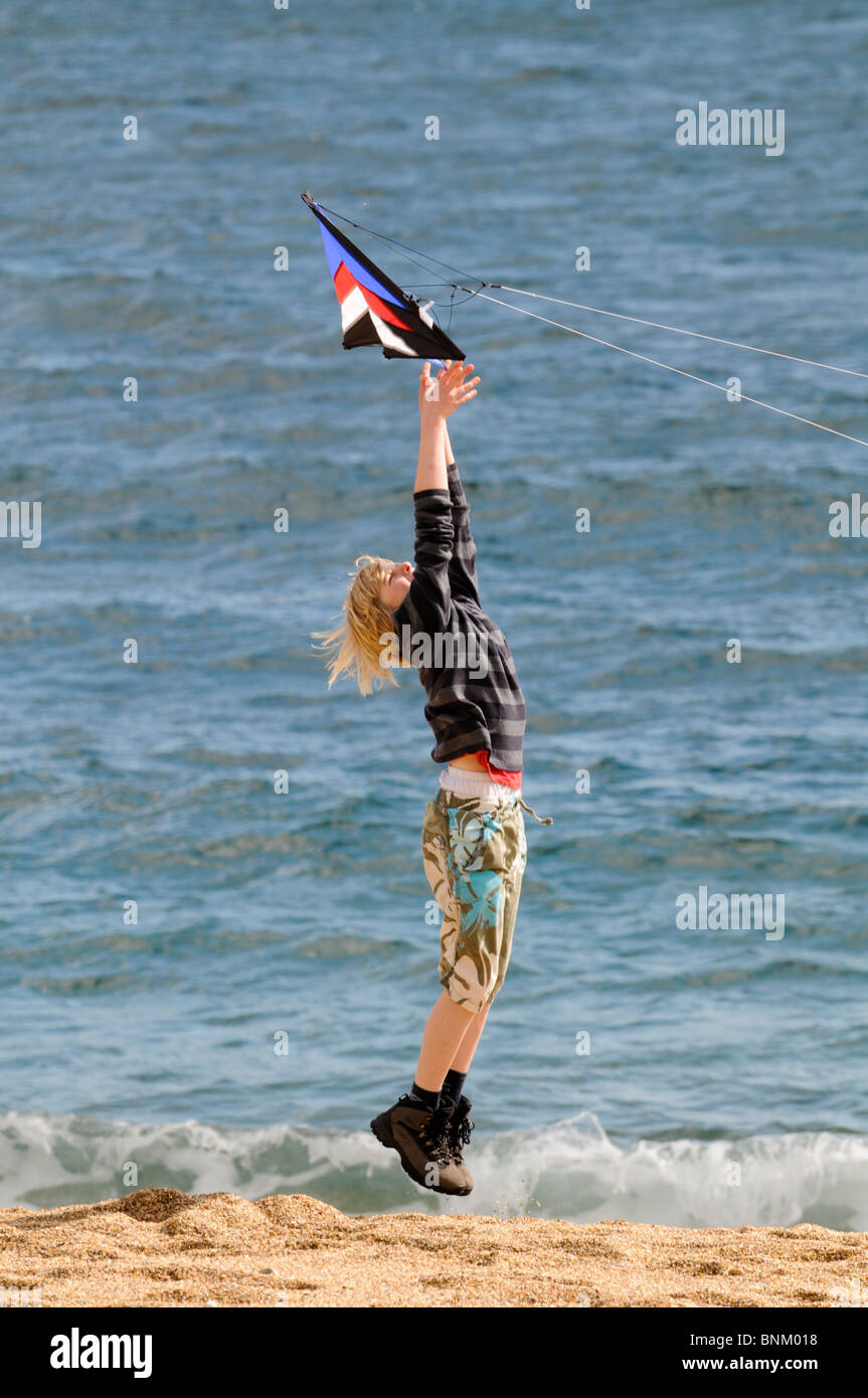 Young boy jumps up and is airborne as he lets go of a kite on a beach ...
