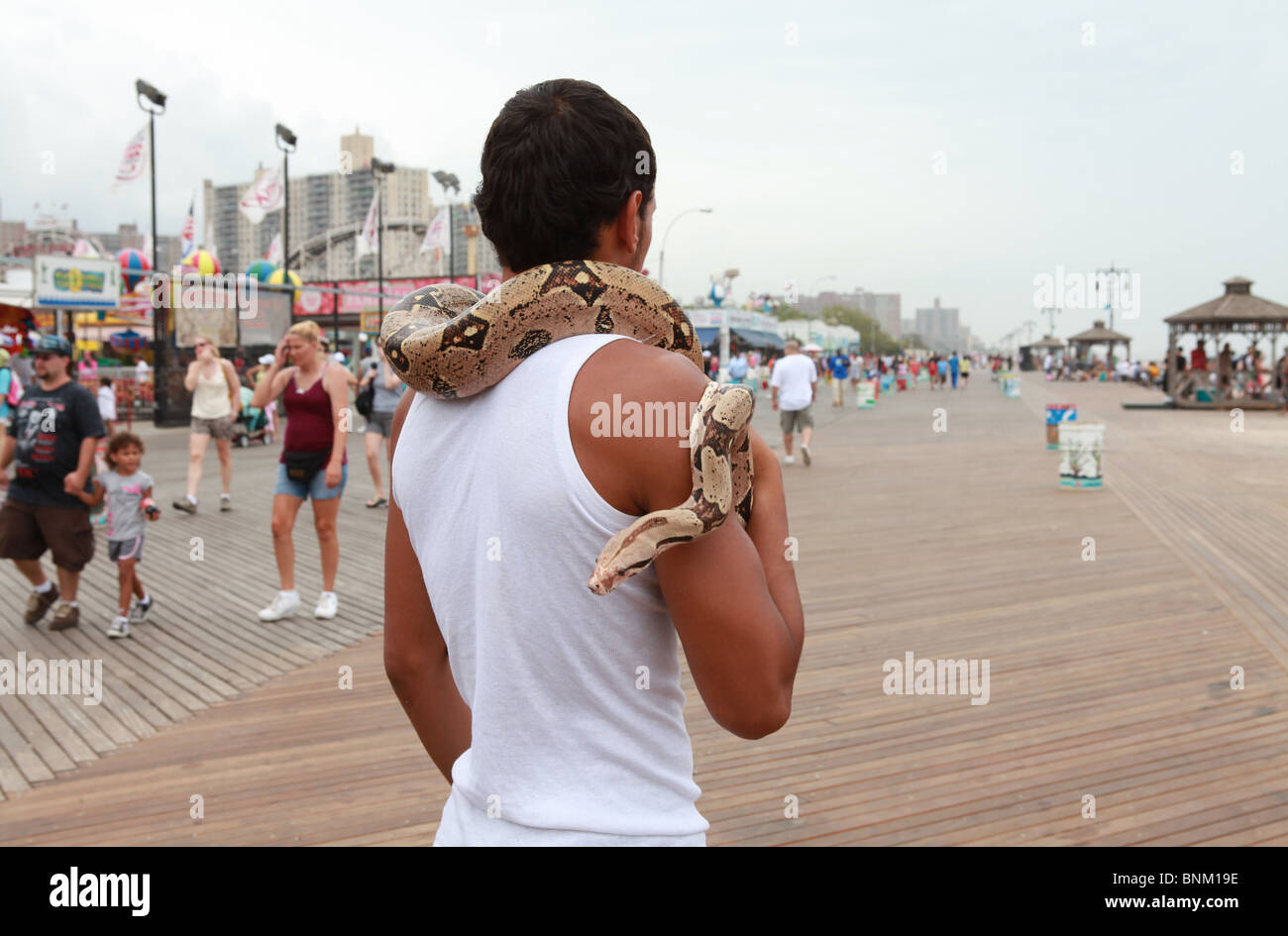 man holding snake on his shoulders on the boardwalk at Coney Island NY ...