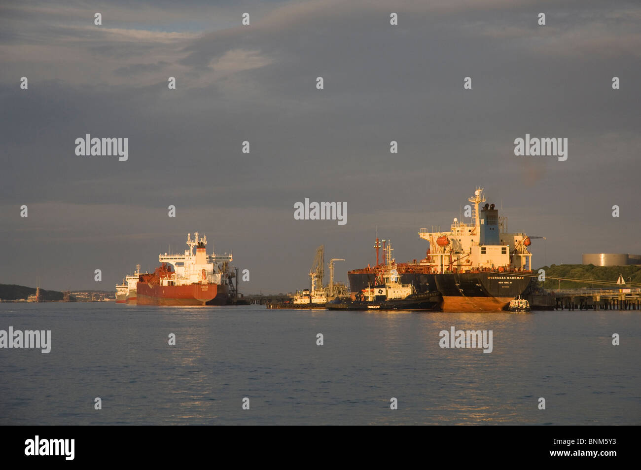 Tugs pushing oil tanker onto jetty, Texaco oil refinery, Milford Haven ...