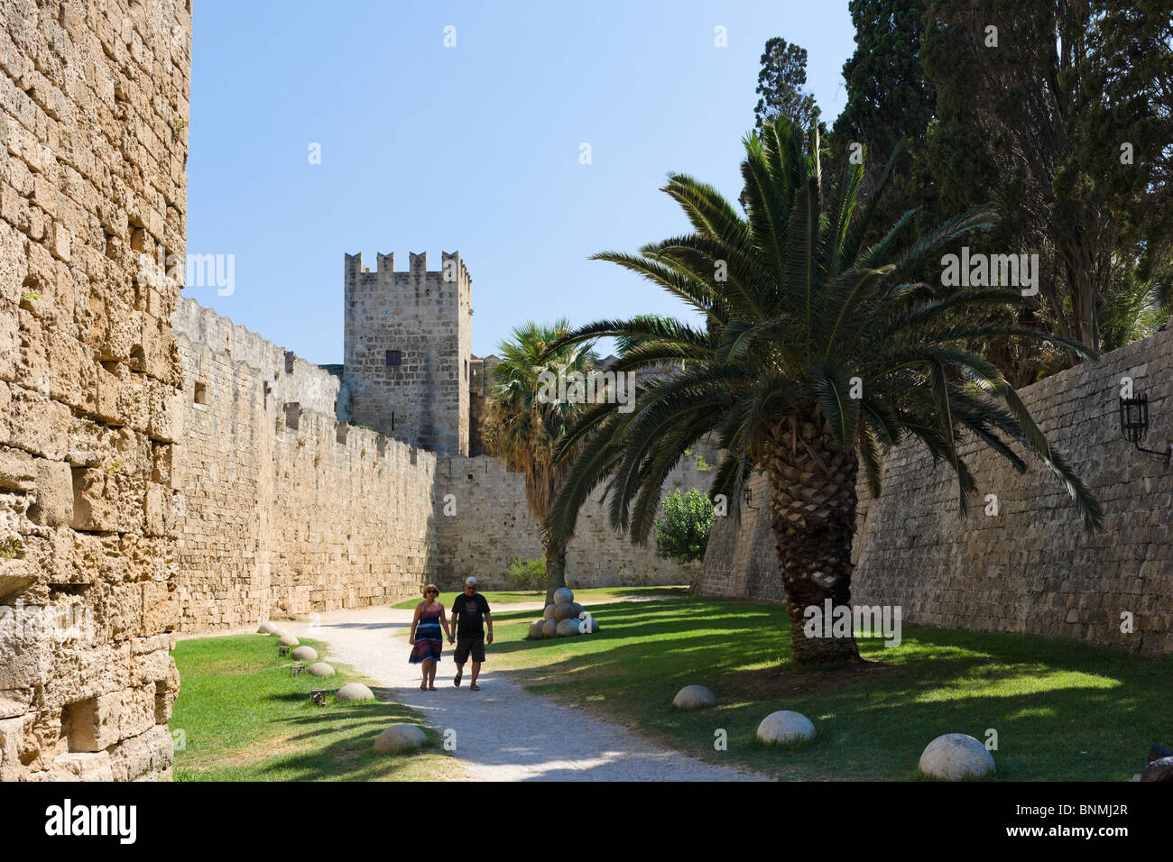 Couple walking along the path in the Medieval moat round the walls of ...
