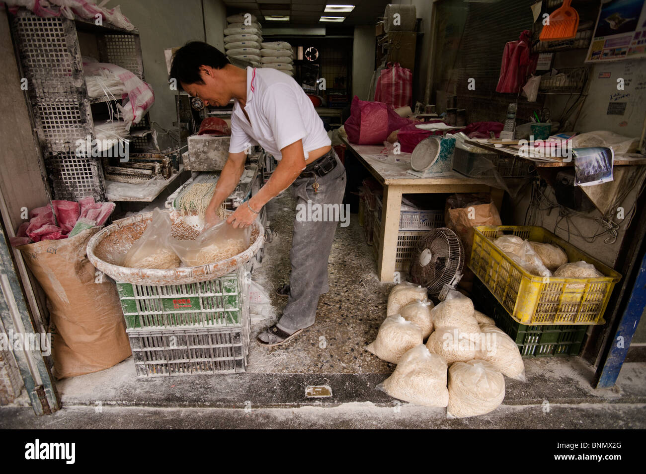 A Taiwanese man bags fresh wheat noodles at a small noodle-making shop ...