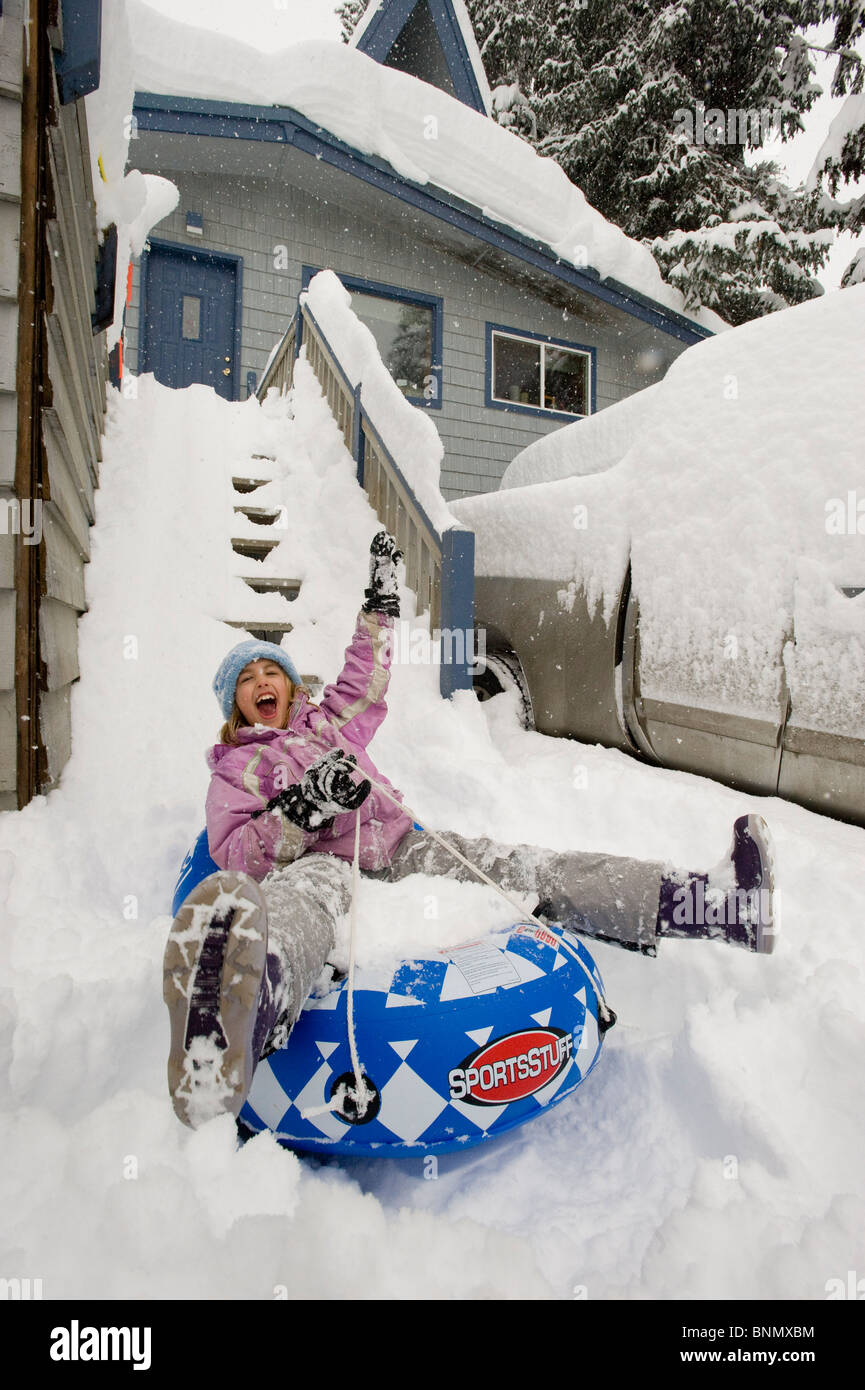 Young girl sleds down her front stairs of her house in Alaska during ...