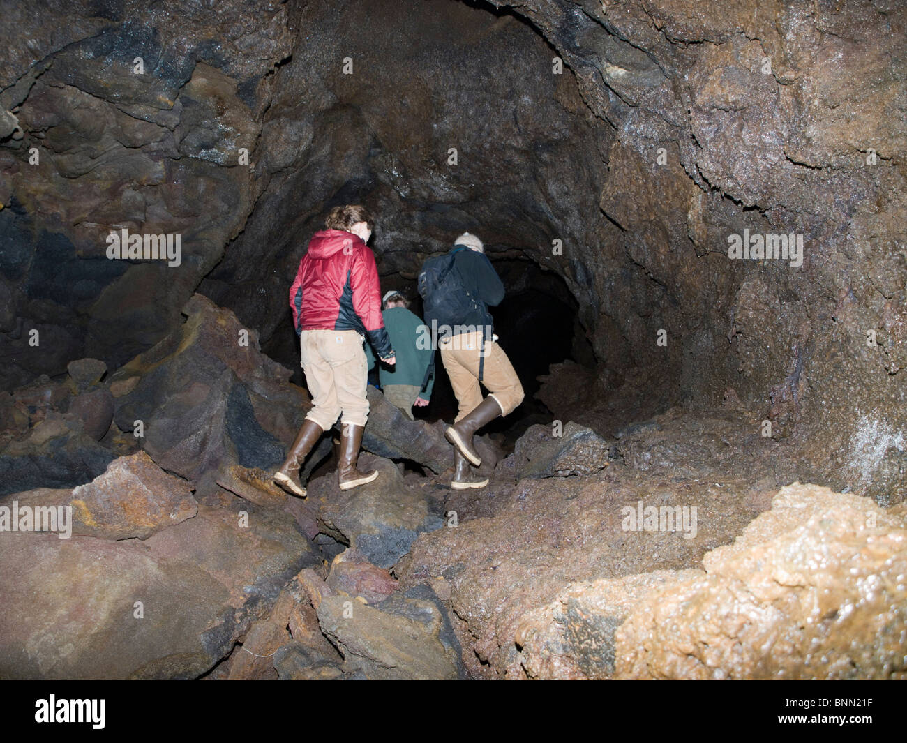 Hikers explore a cave formed by lava flows inside a former volcano, St ...