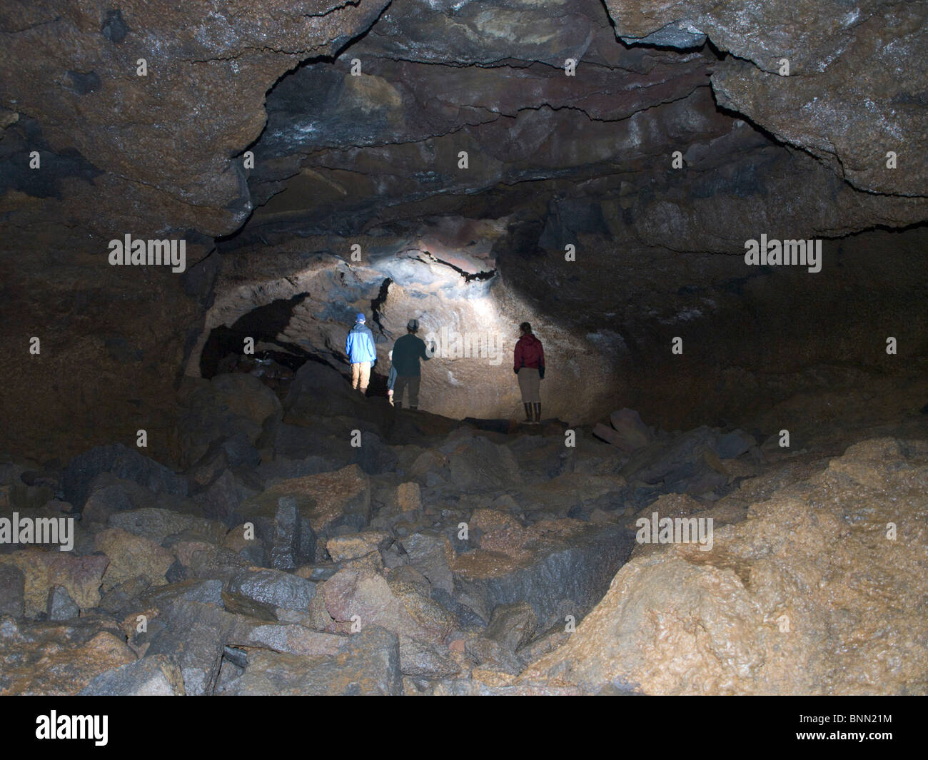 Hikers explore a cave formed by lava flows inside a former volcano, St ...