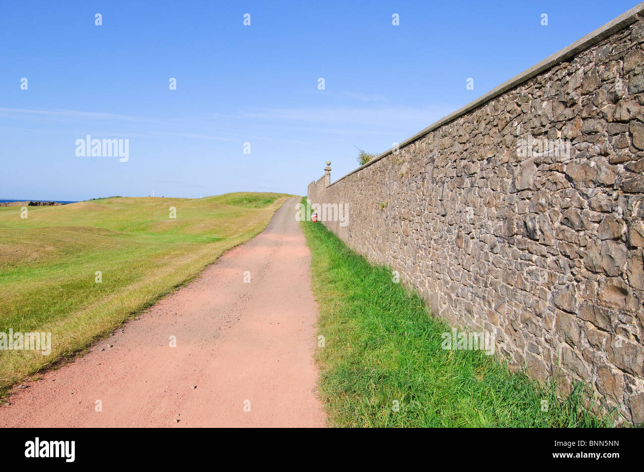 A long stone wall separating private gardens from the golf course in ...