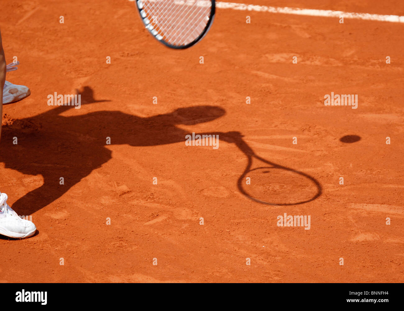 Shadow of a male tennis player on red clay court of Roland Garros ...