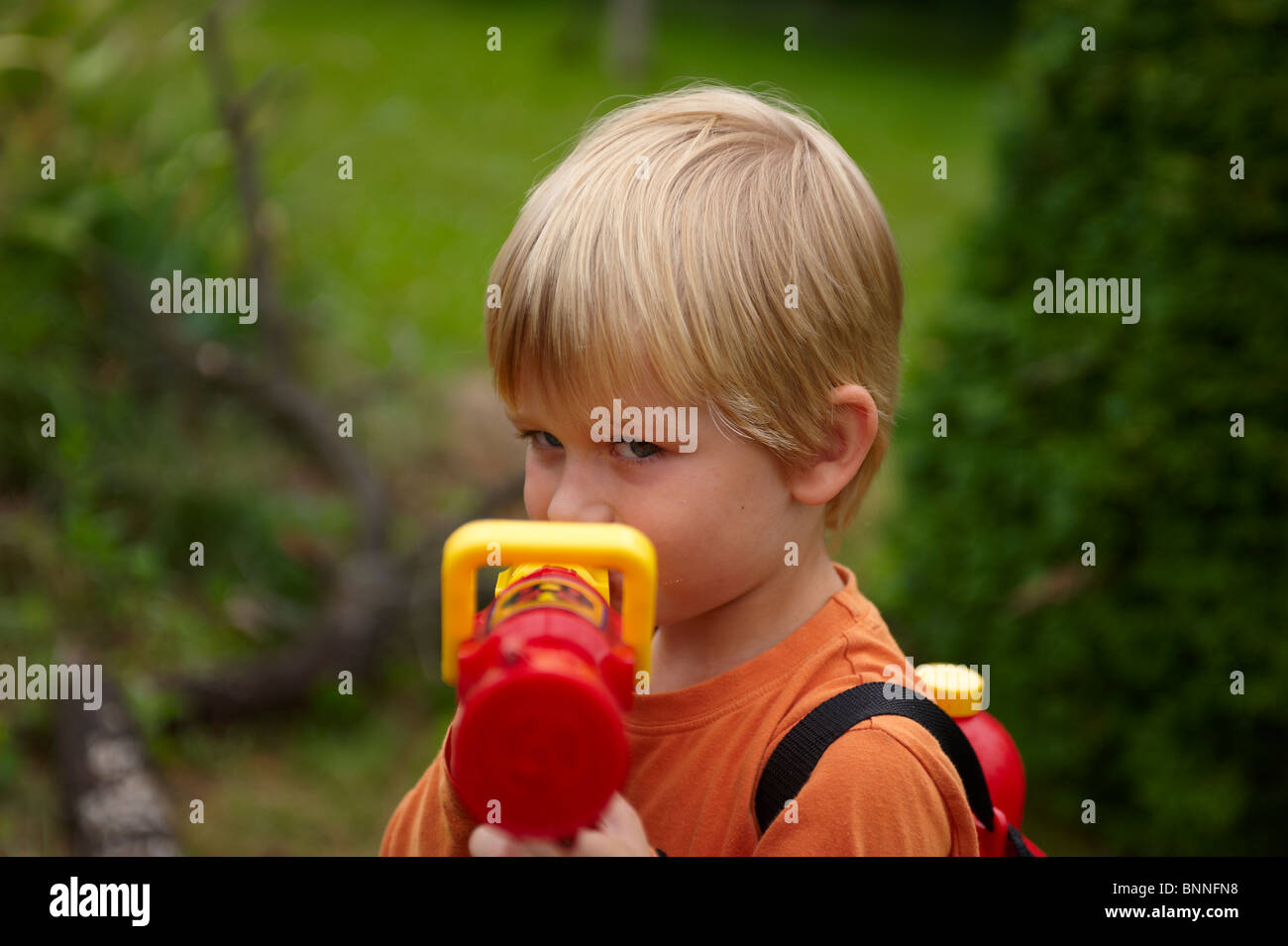 Young child boy playing fire fighter garden Stock Photo - Alamy