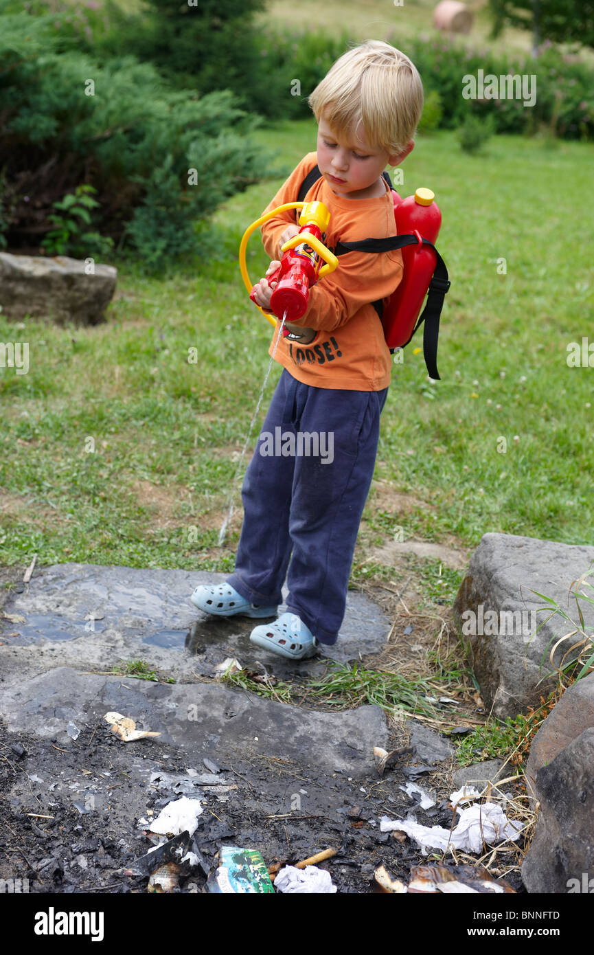 Young child boy playing fire fighter garden Stock Photo - Alamy